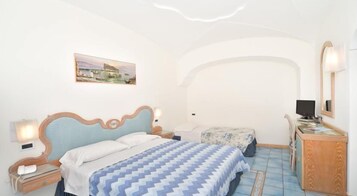 Quarto com cama, mesa de cabeceira e escrivaninha com computador.