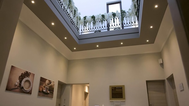 Uma sala de jantar com mesas preparadas para hóspedes, teto com iluminação embutida e vista do céu através da grade da varanda.
