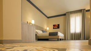 Quarto de hotel com cama, abajures, um quadro e uma janela grande com cortinas.