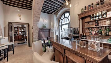Uma área de bar com balcão de madeira, prateleiras com garrafas de bebidas e um espaço de estar com bancos e cadeiras.