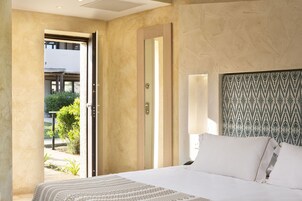 Quarto de hotel com uma cama, uma porta que dá para o exterior e cabeceira estampada.