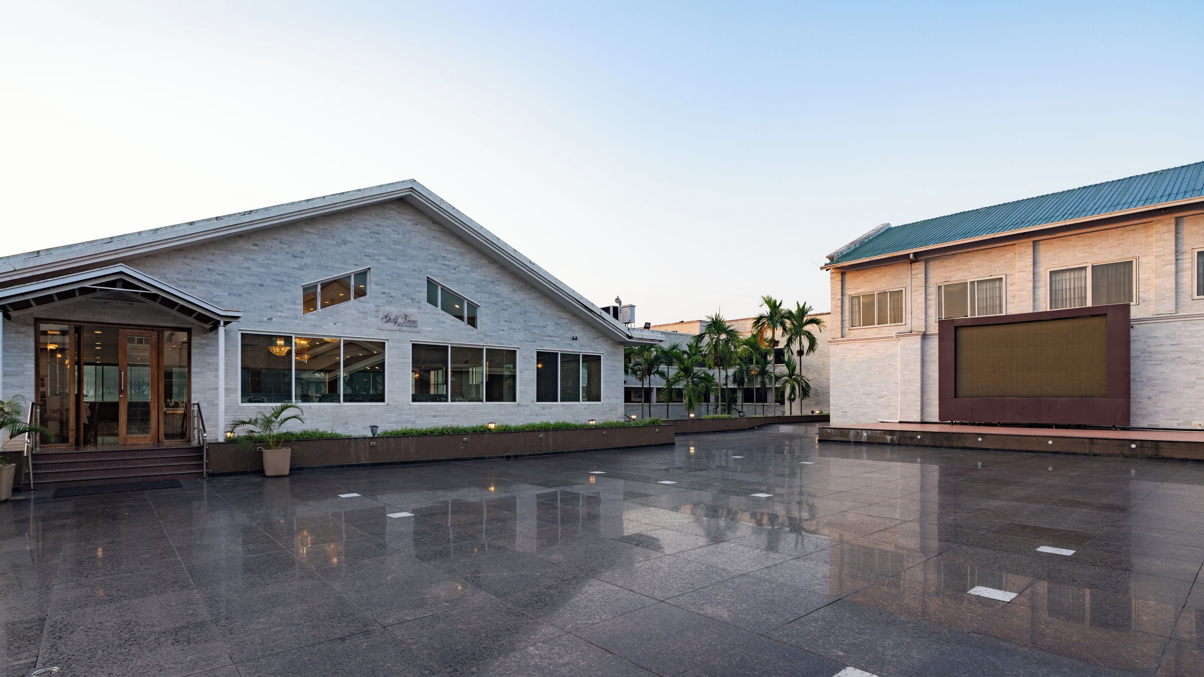 Um edifício moderno com fachada de vidro, telhado plano e grande entrada.