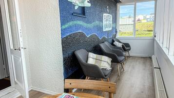 Quarto com parede azul texturizada, uma mesa de madeira com um brinquedo de barco Skipper e vista para casas pela janela.