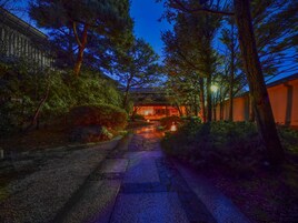 Um edifício japonês tradicional com um caminho de pedra que leva a uma construção de madeira.