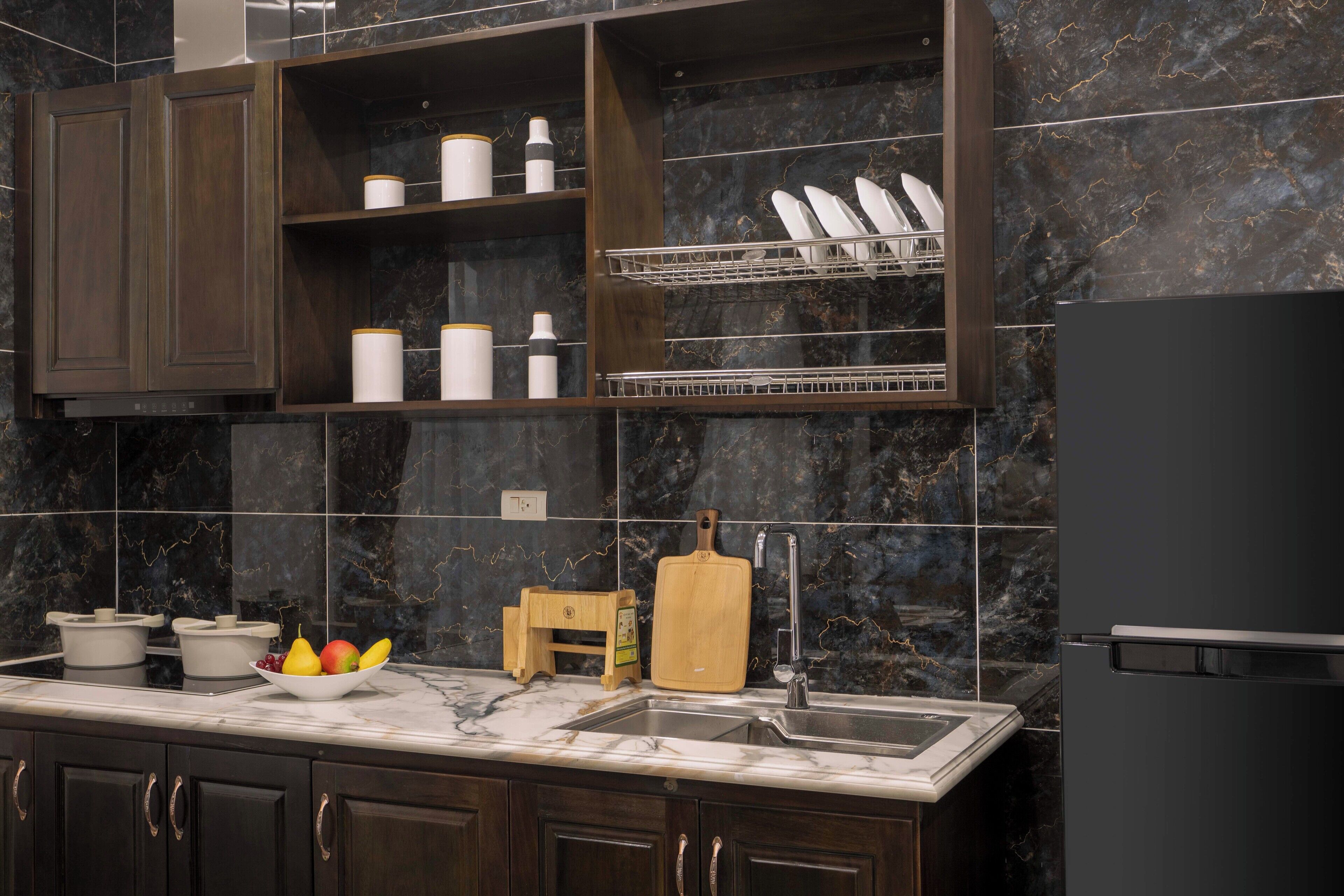 Cozinha moderna com armários de madeira escura, painel de fundo de mármore e pia de aço inoxidável.