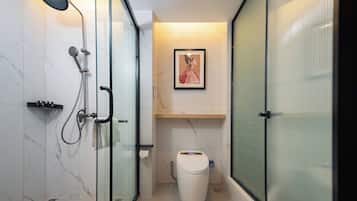 Uma casa de banho moderna com cabine de duche em vidro, sanita e um quadro emoldurado na parede.