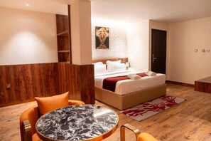 Quarto de hotel com cama, mesa redonda e sofá.