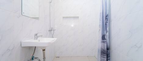 Casa de banho com lavatório branco, chuveiro e espelho.