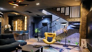 Uma sala de estar moderna com sofá, mesa de centro, poltrona amarela e escada que dá para um andar superior.