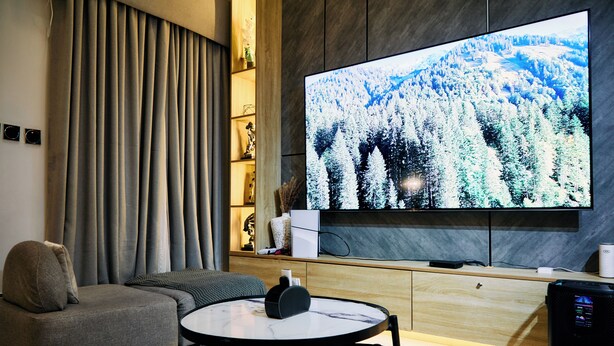 Uma sala de estar moderna com uma grande televisão de tela plana, um sofá, uma mesa de centro e um armário.