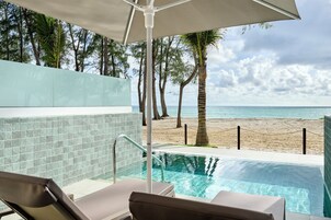 Área da piscina com espreguiçadeiras e vista para a praia.