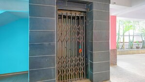 Um portão de metal com padrão decorativo, embutido em um edifício com paredes e chão de azulejos escuros.