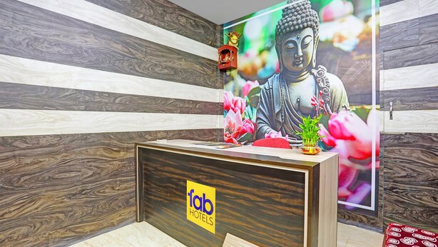 Balcão de recepção com estátua de Buda, um pequeno santuário e o logotipo da 'fab hotels'.
