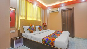 Quarto de hotel com uma cama, mesa de cabeceira, espelho, aparelho de ar condicionado e uma porta.