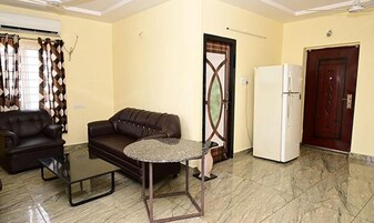 Sala de estar com sofá, mesa de centro, geladeira e porta com detalhe decorativo.