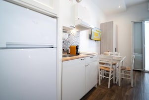 Uma cozinha moderna com armários brancos, bancada de madeira e uma área de refeições com cadeiras brancas.