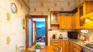 Uma cozinha com armários de madeira, um fogão e uma televisão. Há uma janela com vista para a cidade e montanhas.