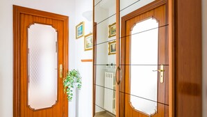 Uma porta de madeira com painel de vidro jateado, um radiador branco e uma planta em vaso.