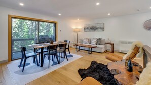 Uma sala de estar moderna com área de jantar, janelas amplas, sofá e lareira.