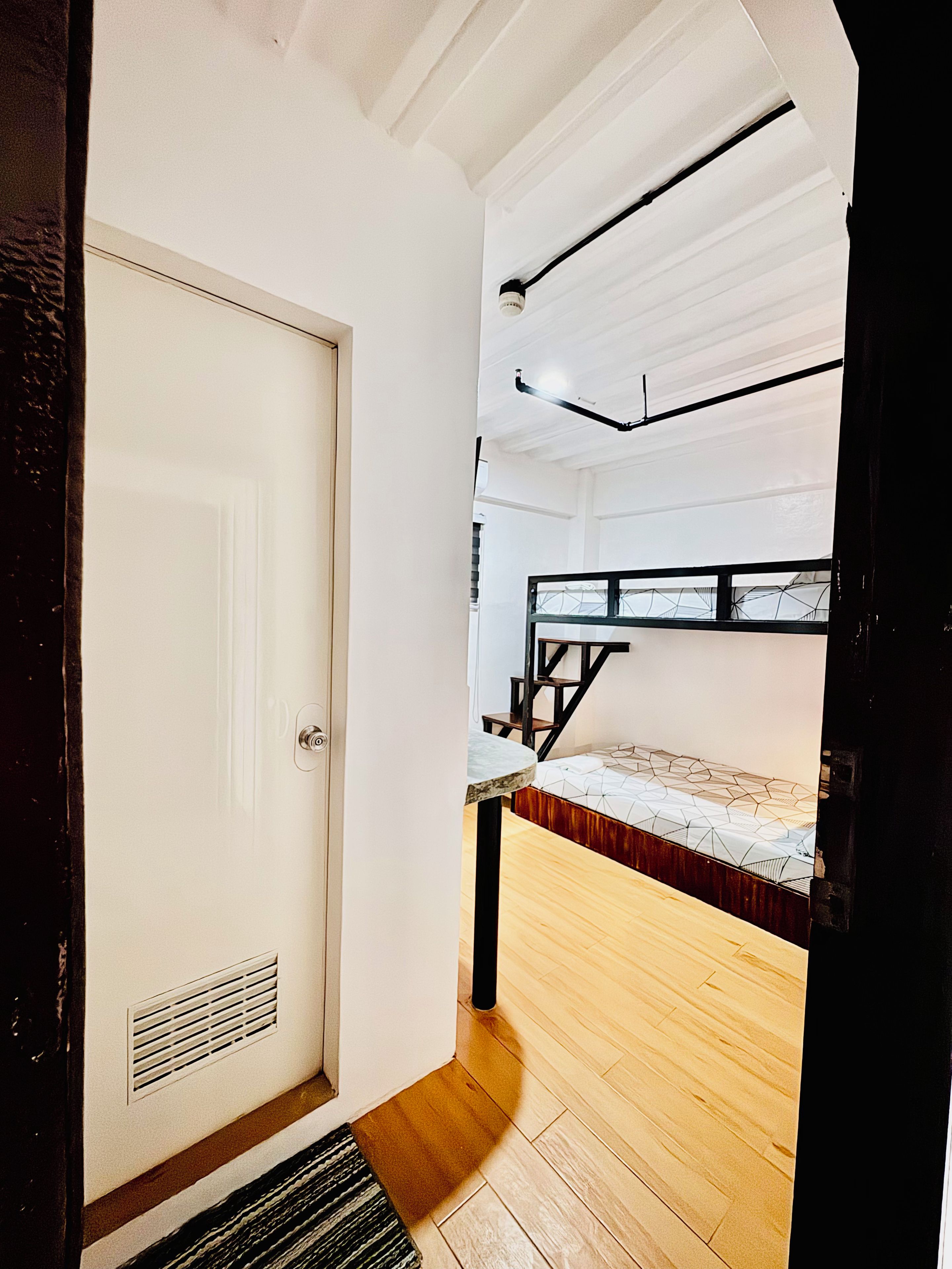 Quarto com beliche, porta e escada.