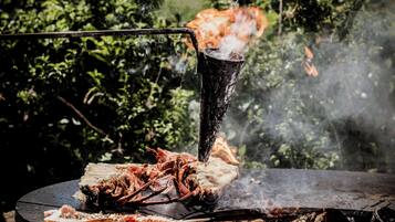 Uma churrasqueira com frutos do mar e carne a ser preparada ao ar livre.