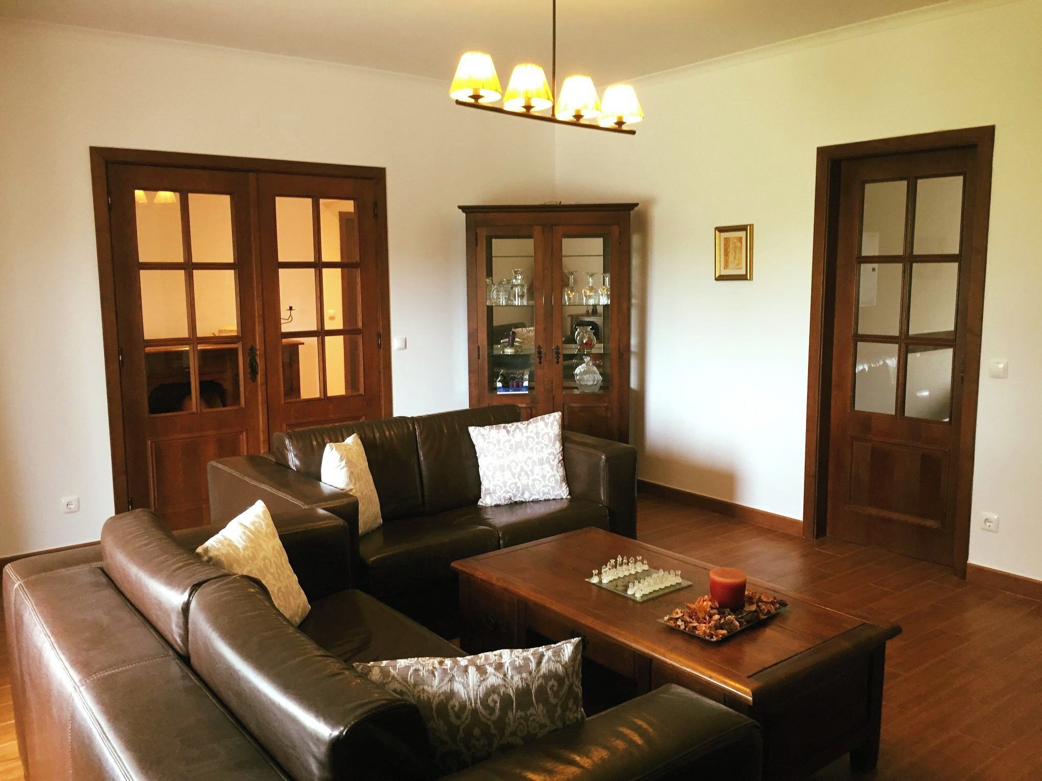 Uma sala de estar com um sofá de couro marrom, uma mesa de centro de madeira e um candelabro.