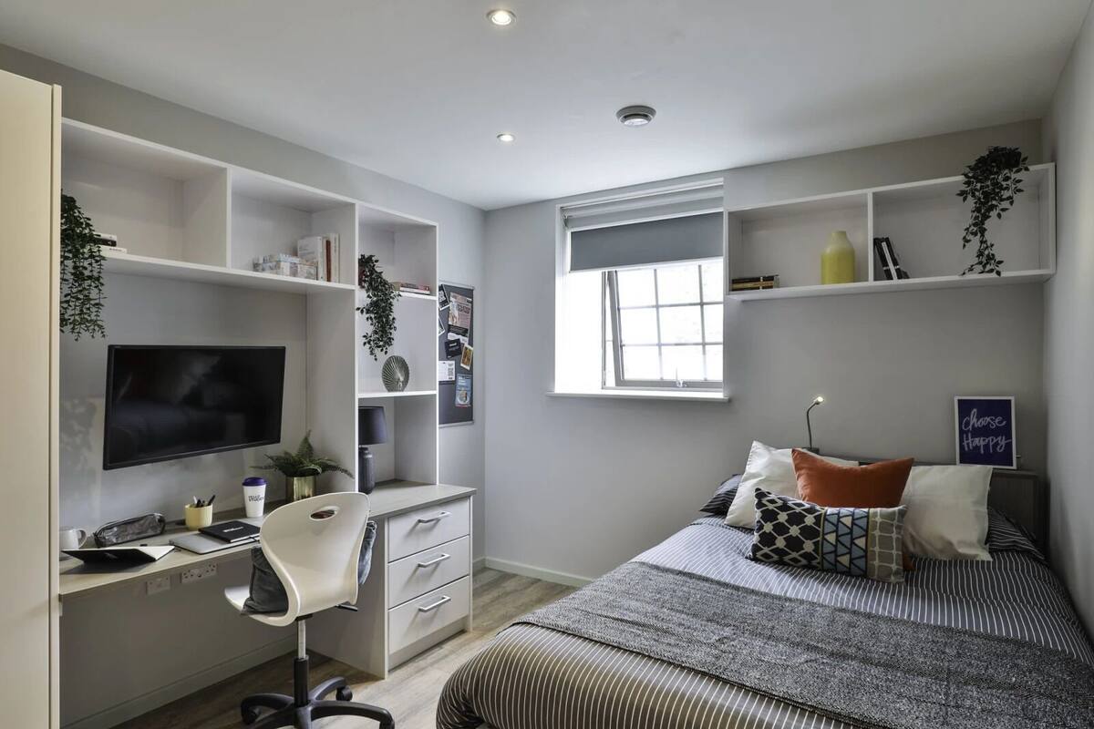 Quarto moderno com escrivaninha, cama e estantes.