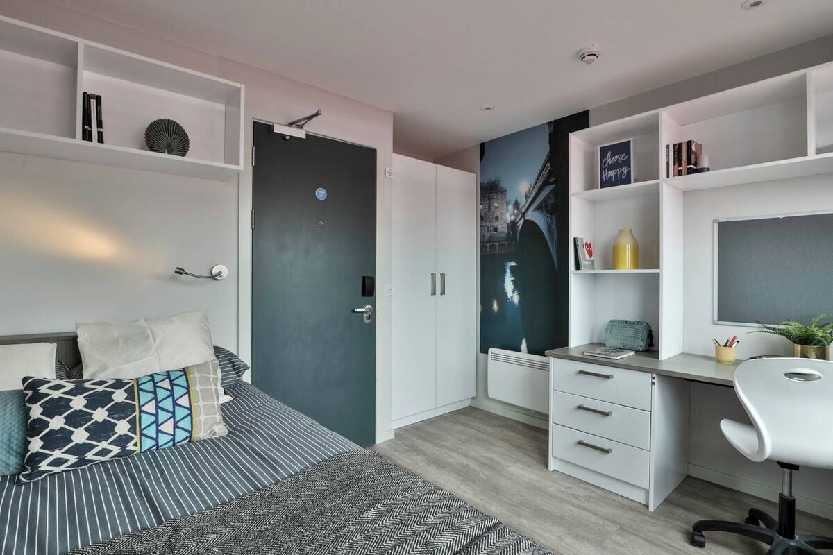 Quarto moderno com cama, escrivaninha e estantes.