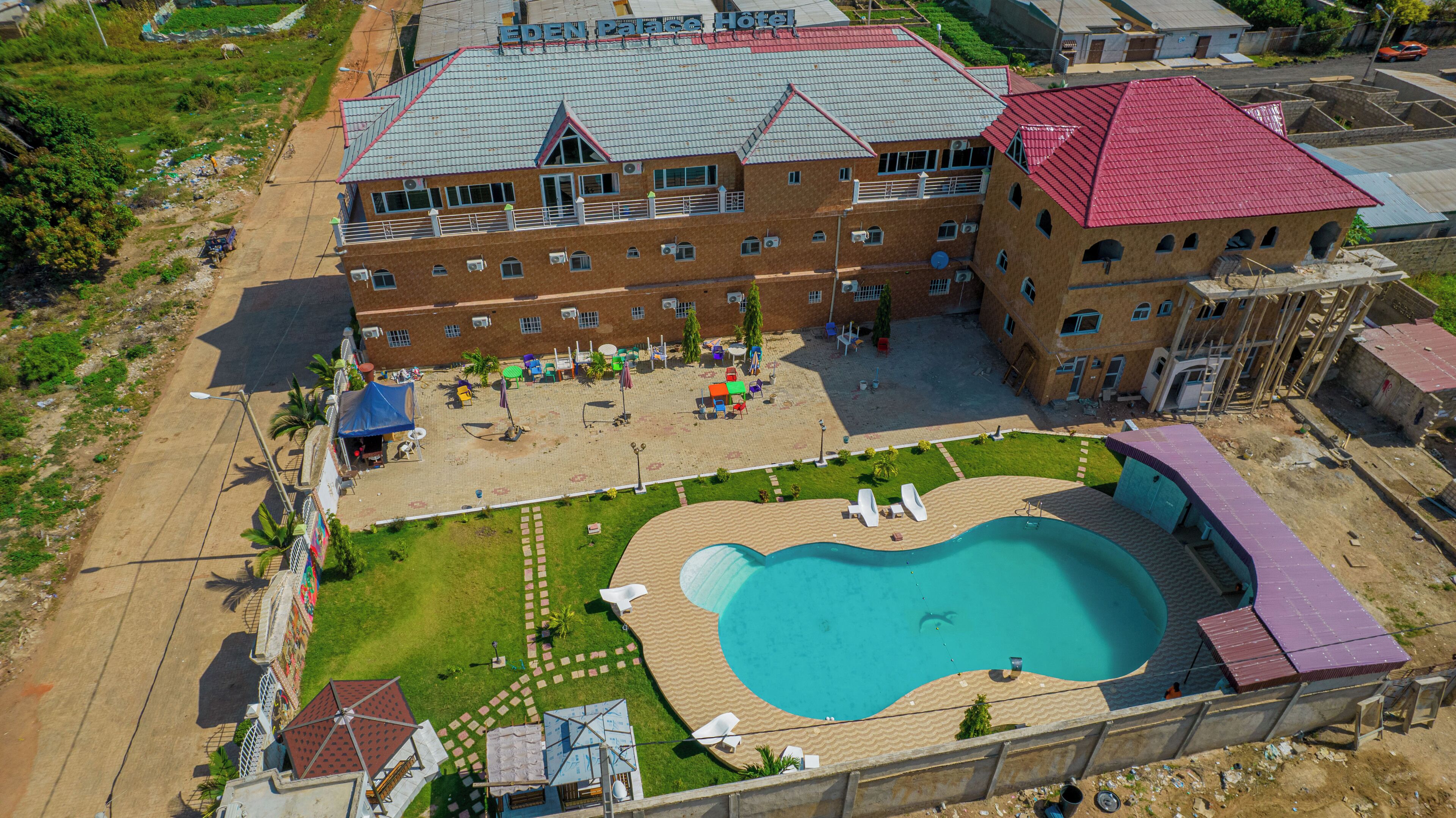 Um hotel com piscina, área de estar ao ar livre e um edifício grande com várias janelas.