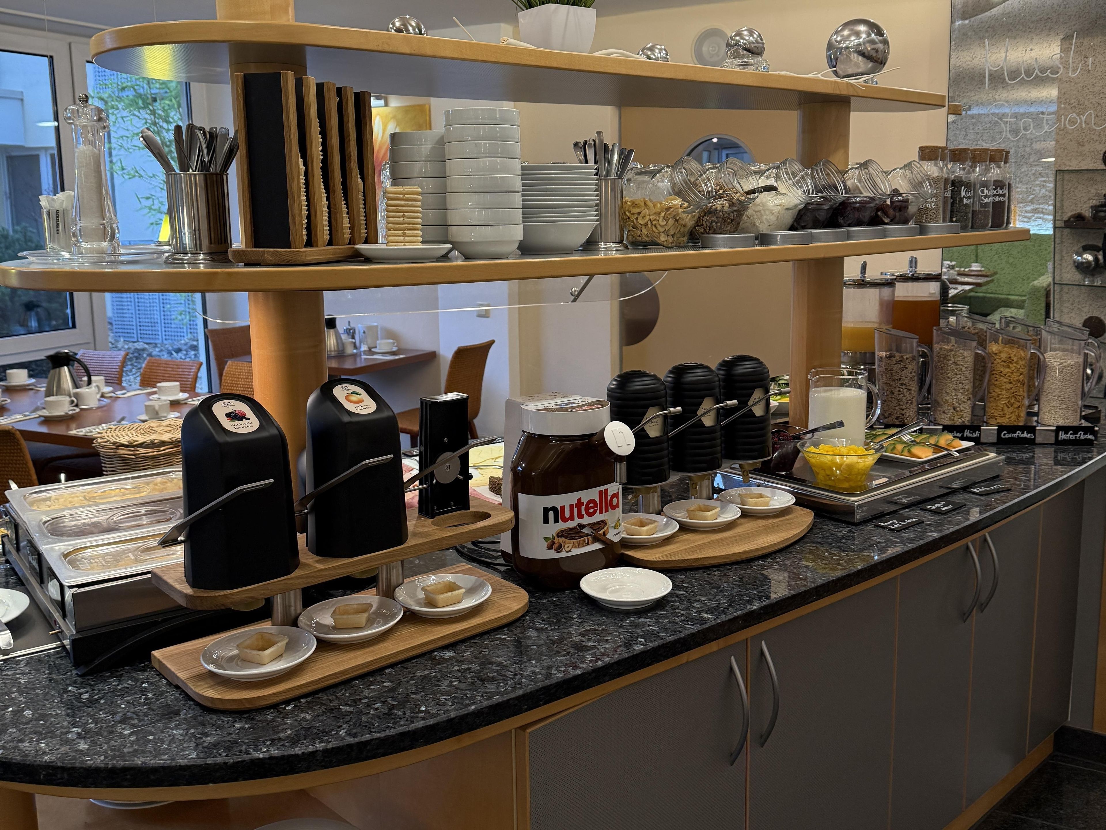 Disposição de buffet com diversos alimentos, acompanhamentos e utensílios de servir.