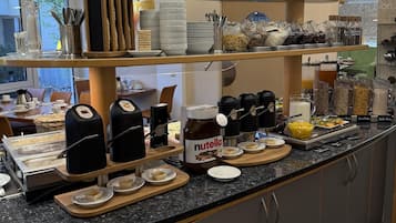 Disposição de buffet com diversos alimentos, acompanhamentos e utensílios de servir.