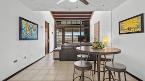 Uma sala de estar moderna com uma mesa de jantar redonda, quatro banquetas, um sofá e um ventilador de teto.