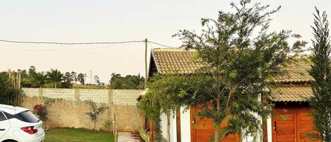 Um caminho leva a um edifício com telhado em telhas e porta de madeira.