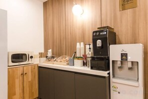 Cozinha compacta com micro-ondas, cafeteira e bebedouro.