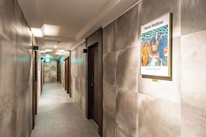 Corredor com uma obra enquadrada de Henri Matisse, parede de mármore e uma porta à direita.