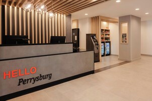 Bancada de recepção com um letreiro 'HELLO PERRYSBURG', caixa registradora, geladeira com bebidas e prateleira com lanches.