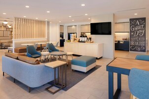 Uma sala de estar moderna com sofá, cadeiras, mesa de centro e cozinha, incluindo TV e balcão.