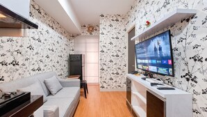 Uma sala de estar moderna com um sofá cinzento, uma televisão de ecrã plano fixada na parede e chão de madeira.