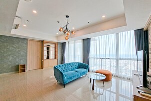 Uma sala de estar espaçosa com um sofá azul, uma mesa de centro redonda e um candelabro moderno.
