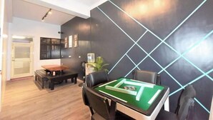 Um quarto com uma mesa de bilhar, um banco de madeira e uma parede preta com padrões geométricos.