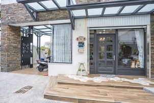 Uma casa moderna com fachada de pedra, porta de garagem e uma grande porta de vidro deslizante que dá para um alpendre coberto.