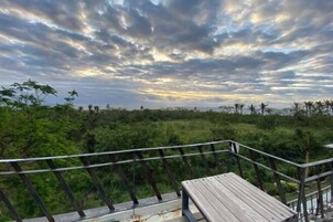 Um deck de madeira com guarda-corpo de metal com vista para uma paisagem verdejante.