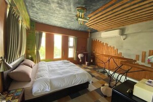 Quarto com cama, escrivaninha, cadeira e janela.
