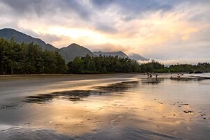 Uma praia com montanhas ao fundo e céu claro.