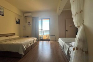Quarto de hotel com duas camas, varanda e vista para o mar.