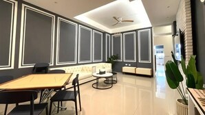 Uma sala de jantar moderna com uma mesa comprida, cadeiras, um ventilador de teto e um sofá.