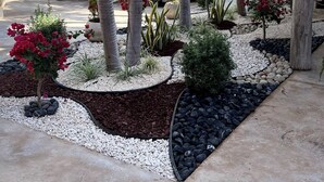 Um jardim bem cuidado com palmeiras, diversas plantas e uma construção de palha.