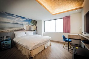 Quarto de hotel moderno com uma cama grande, uma escrivaninha, uma cadeira e uma janela com vista para a praia.