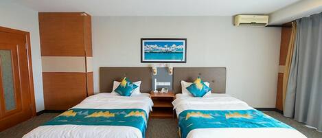 Quarto de hotel com duas camas, um quadro na parede, aparelho de ar condicionado e uma porta.