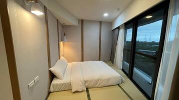 Quarto de hotel com uma cama, uma luminária, uma janela e vista para o exterior.